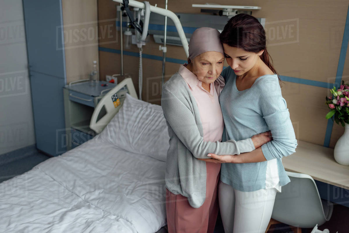 Upset daughter embracing sick senior mother with cancer in hospital ...