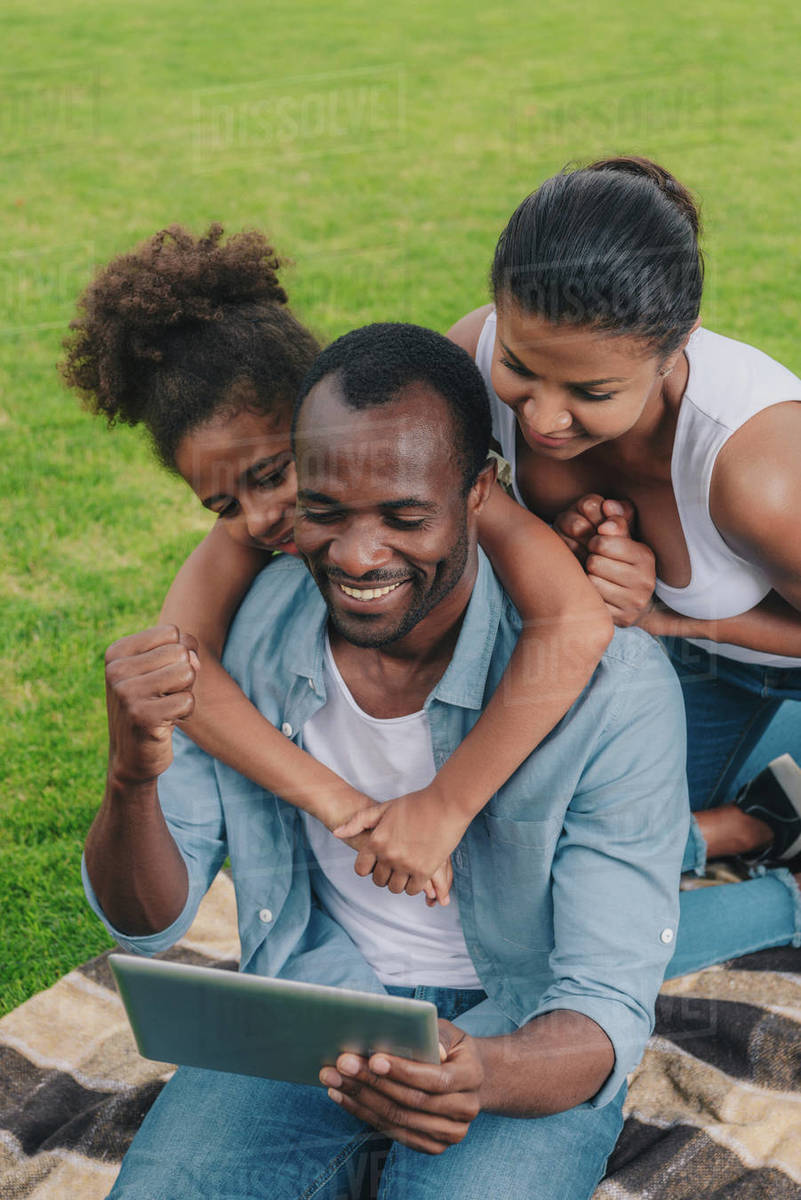 Smiling African American family using digital tablet at countryside ...