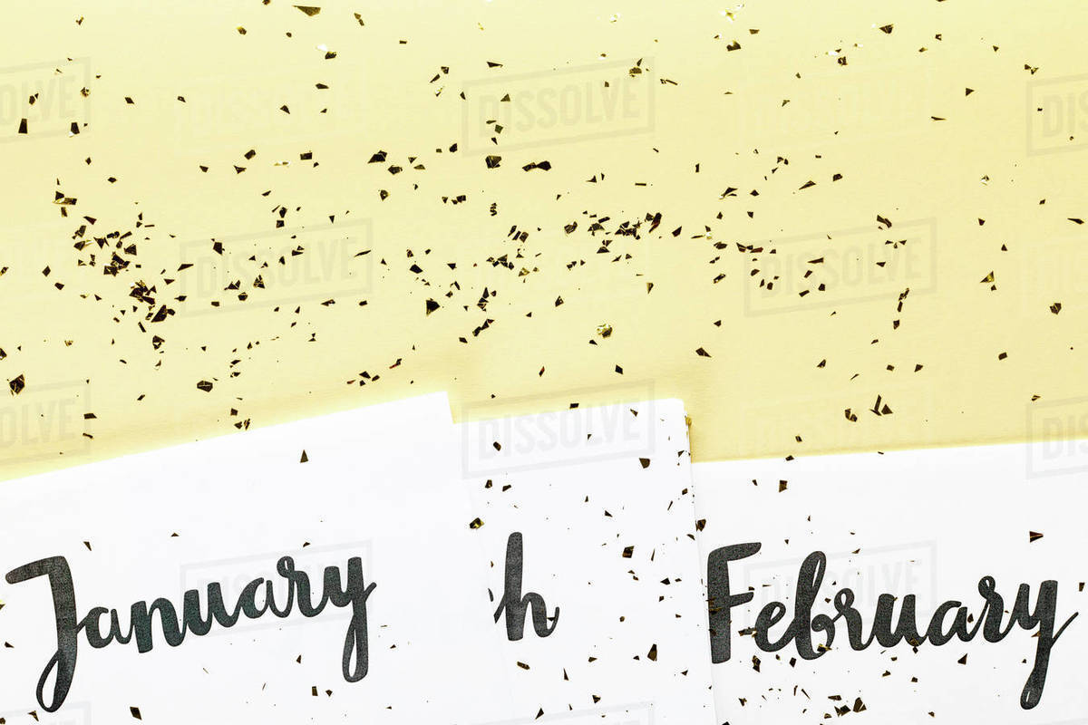 Top view of January and February calendar and golden confetti on beige ...