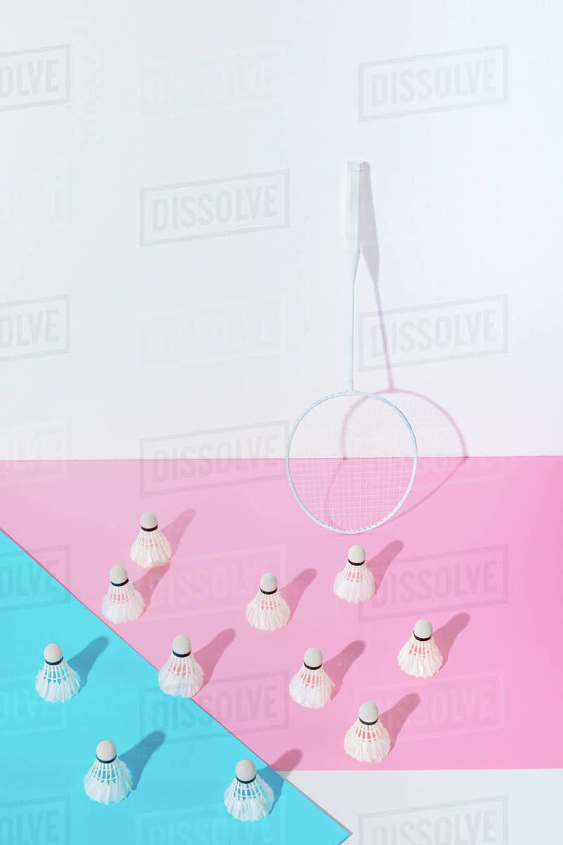 Badminton racket and shuttlecocks on blue and pink papers at wall ...