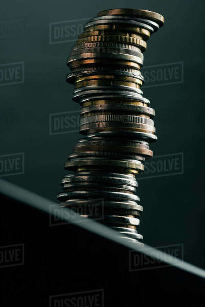 Close up view of stack of different coins standing on edge of table ...