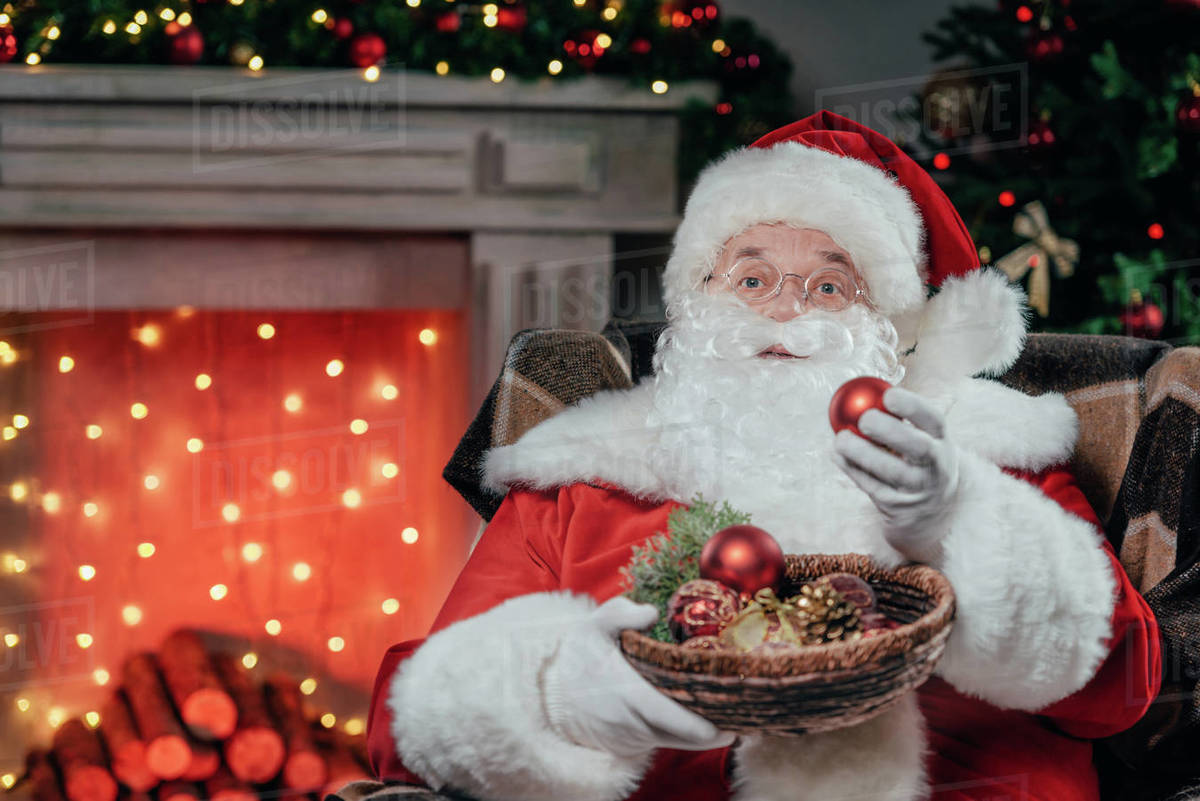 santa claus in traditional red costume holding christmas balls ...