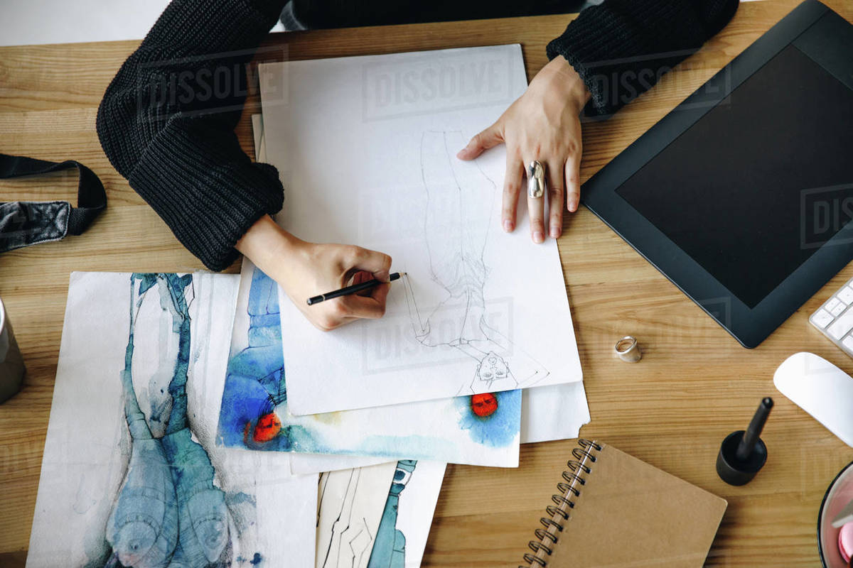 Partial top view of young fashion designer sketching at workplace ...