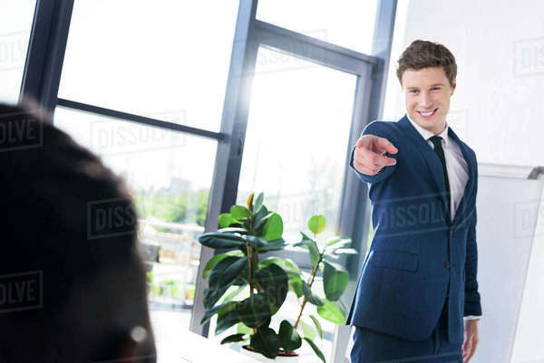 cropped shot of handsome smiling young businessman pointing at ...