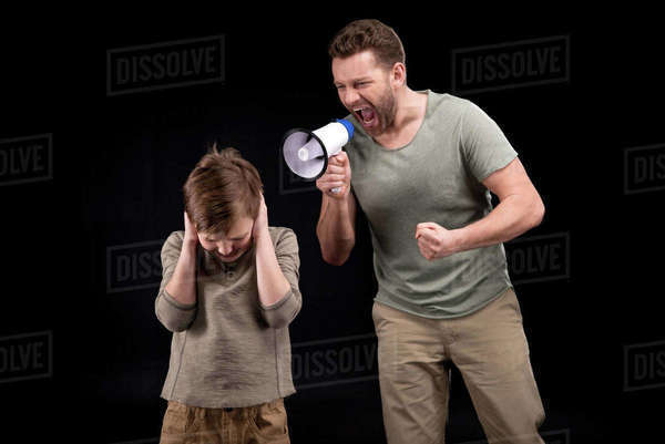 Angry father with megaphone screaming at scared little boy closing ears ...
