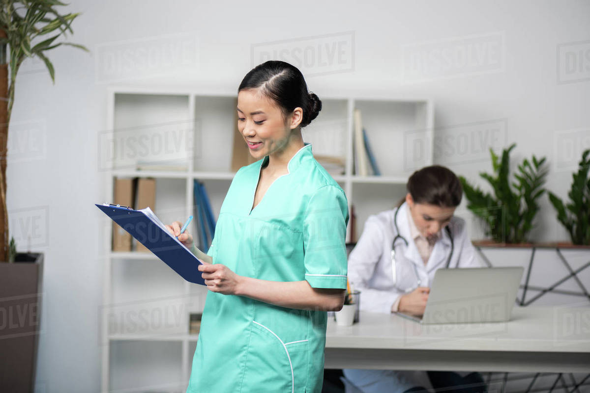 Happy asian internist writing in clipboard with diagnosis, doctor using ...