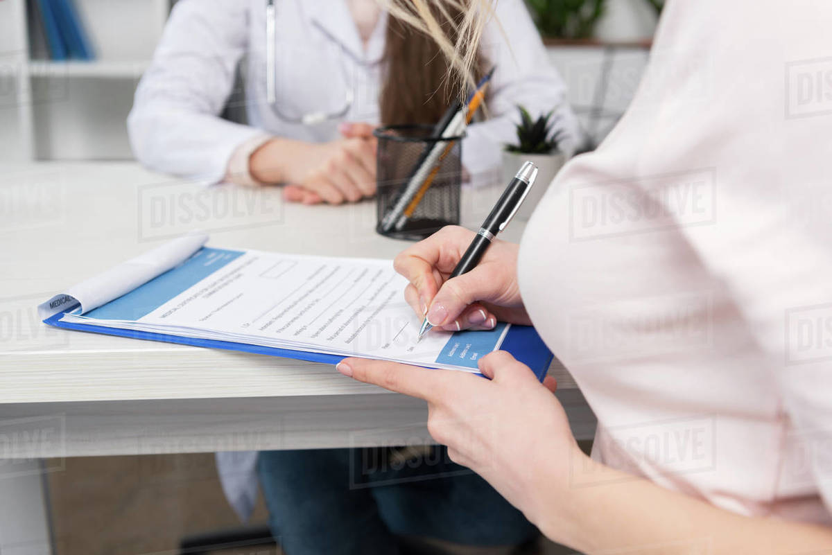 Cropped view of patient filling medical form in professional clinic ...