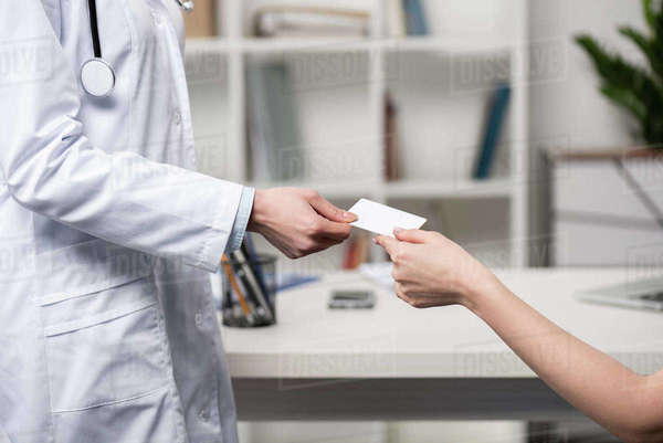 Partial view of doctor giving blank card to patient at clinic - Stock ...