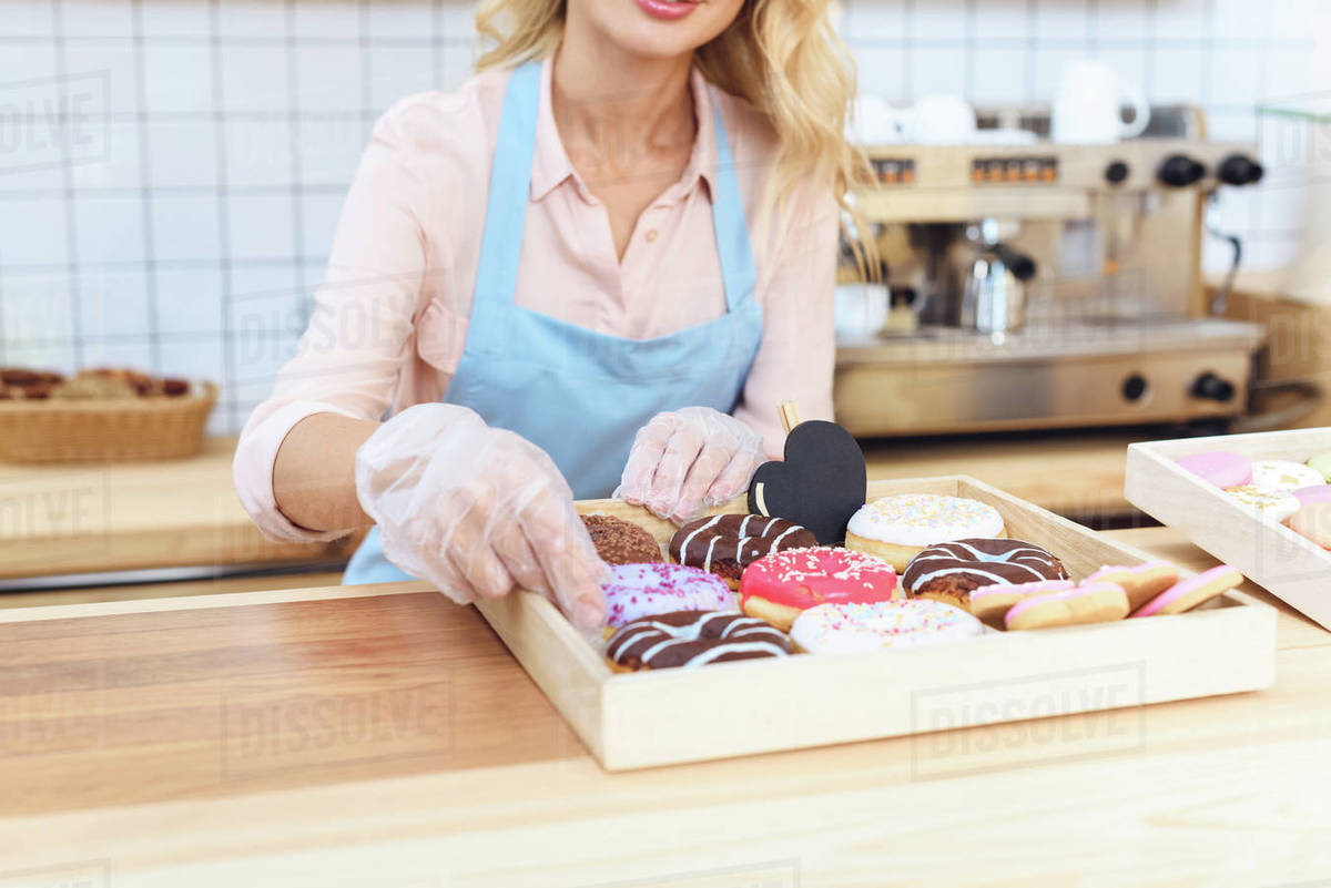 Cropped shot of waitress holding delicious cookies and donuts in box ...
