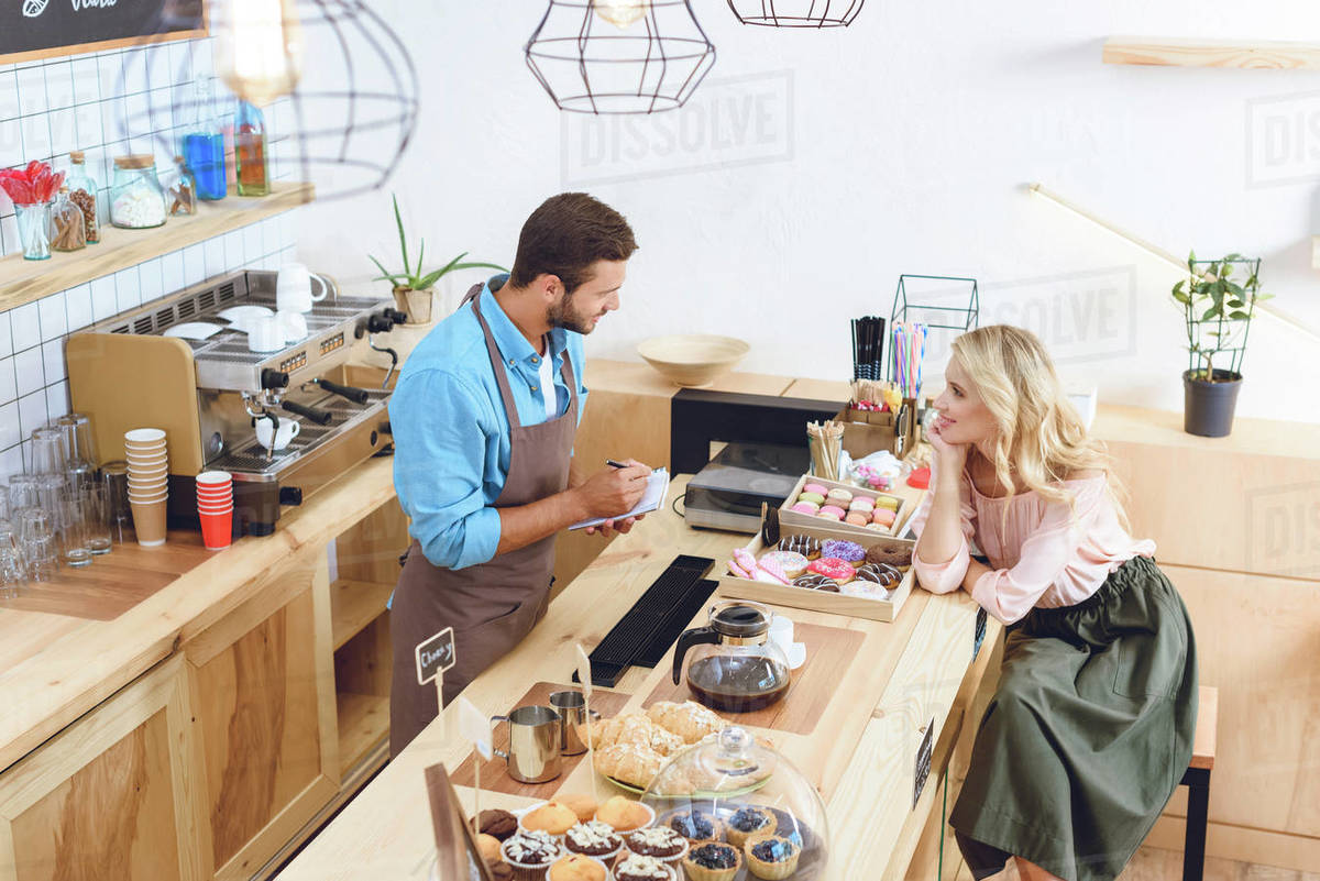 High angle view of handsome waiter taking notes and looking at ...