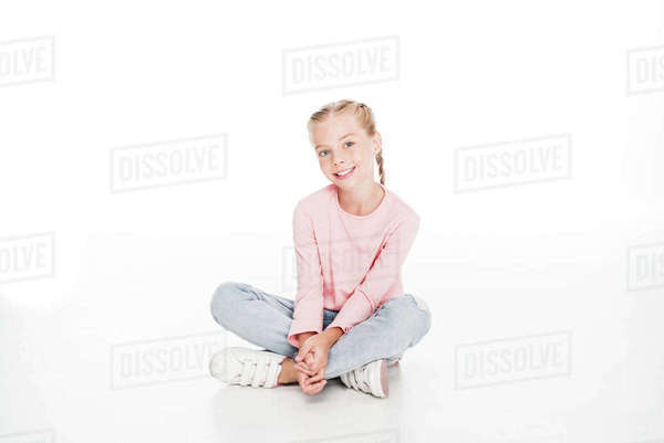 Cheerful child sitting on floor with legs crossed, isolated on white ...
