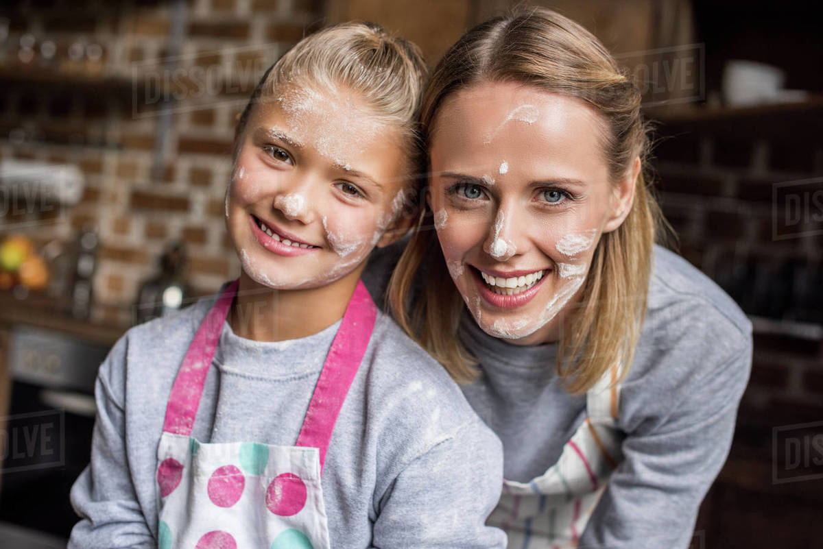 Portrait of happy family with flour on faces looking at camera ...