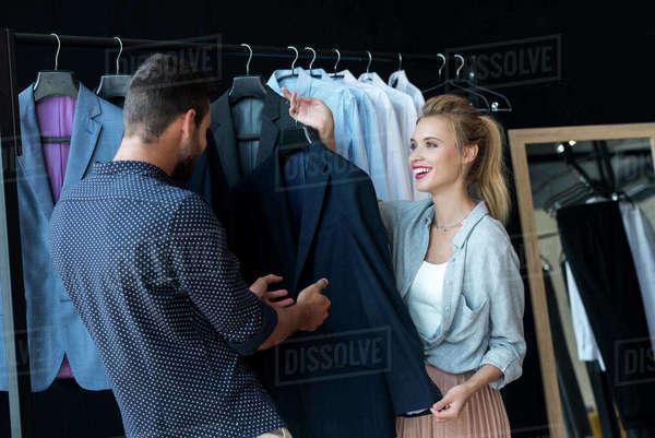 Beautiful happy young couple choosing suit in boutique - Royalty-free ...