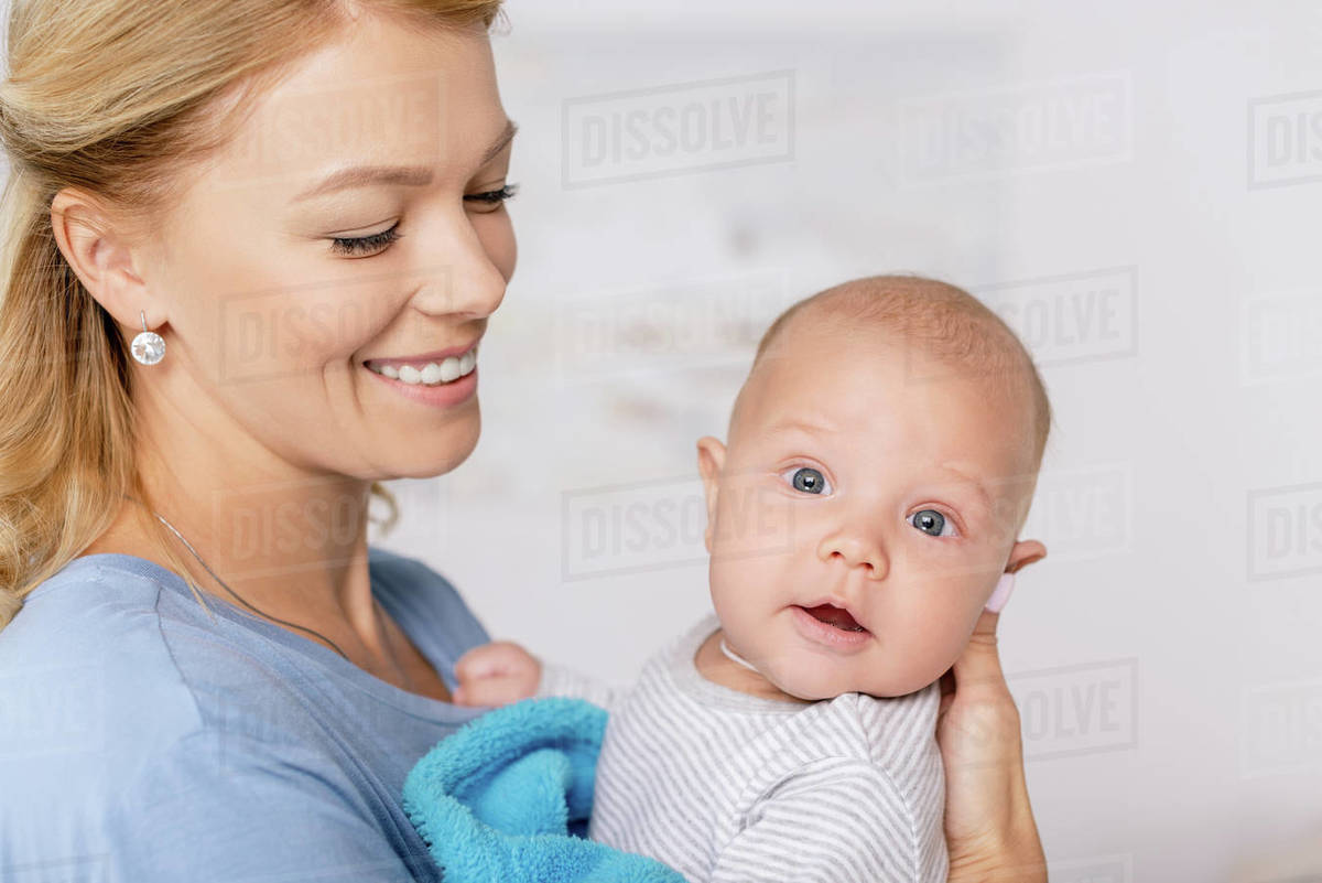 Portrait of smiling mother holding baby in hands at home - Royalty-free ...