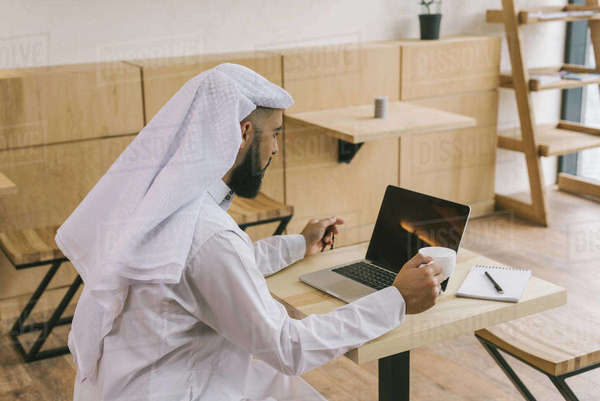 concentrated muslim man in cafe looking at laptop - Royalty-free Stock ...