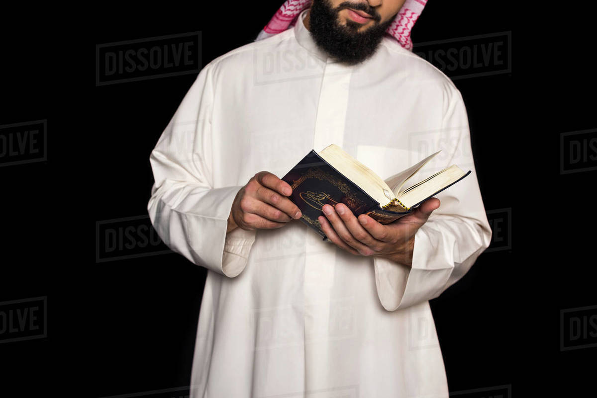 cropped shot of muslim man reading quran isolated on black - Royalty ...