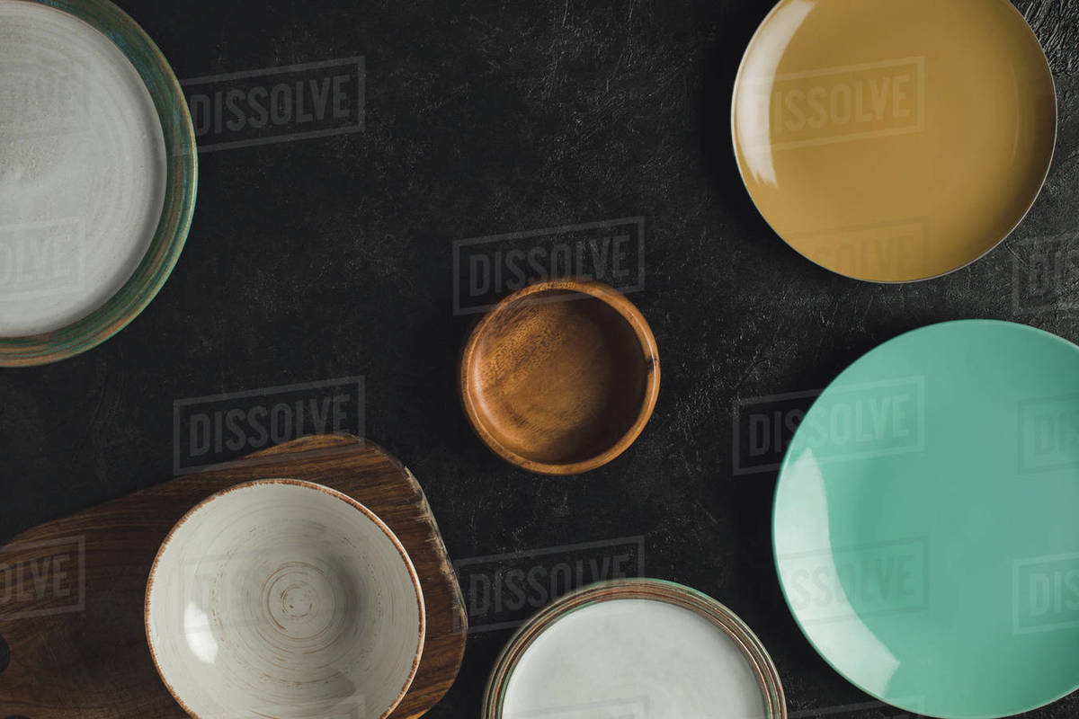 Flat lay with arranged ceramic and wooden plates with cutting board ...