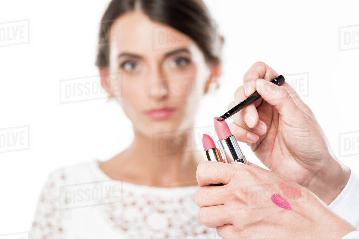 Selective focus of makeup artist holding lipsticks and lip brush in ...