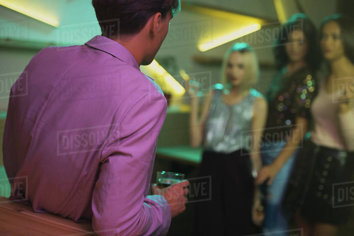 Back view of man with drink in hand leaning on wooden counter - Royalty ...