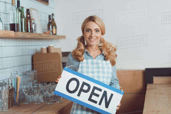 beautiful middle aged waitress holding sign open and smiling at camera ...