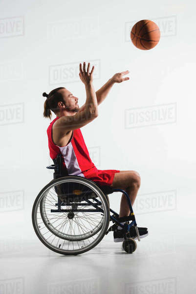 Disabled young sportsman in wheelchair throwing a basketball ball ...