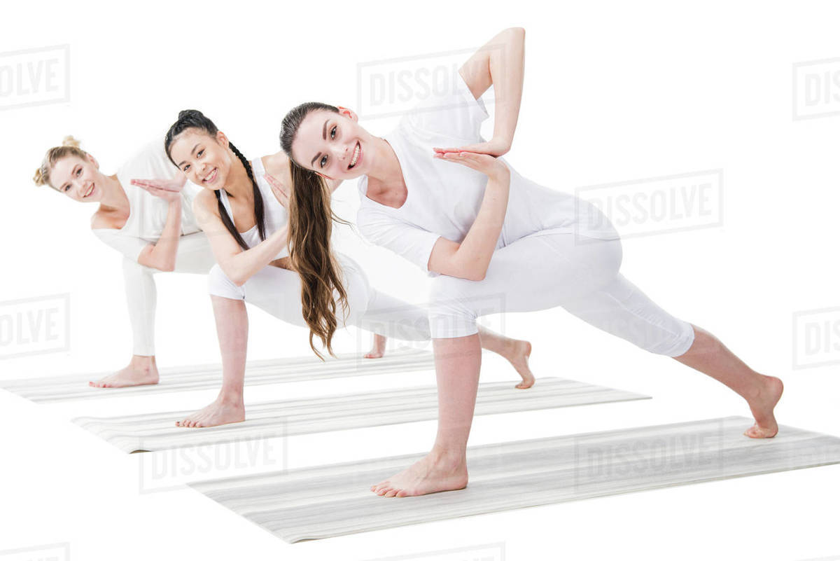 Smiling young women practicing variation of revolved side angle pose ...