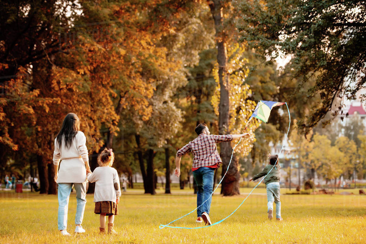 Family with children trying flying a kite in an autumn park - Royalty ...