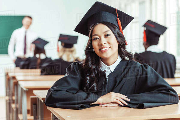 beautiful asian student in graduation costume sitting at classroom ...