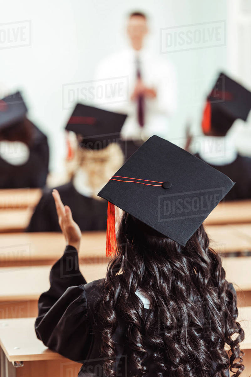 back view of student girl in graduation hat clapping hands while ...