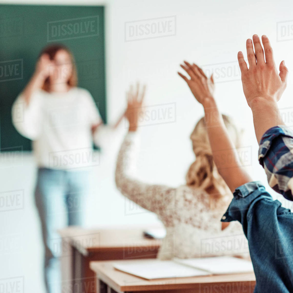 rear view of group of students raising hands in class on lecture ...