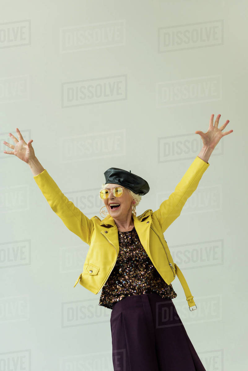 cheerful stylish senior woman in yellow leather jacket and yellow ...