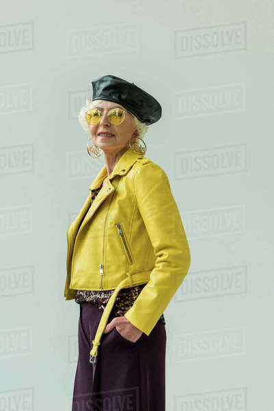 stylish senior woman in yellow leather jacket and yellow sunglasses ...