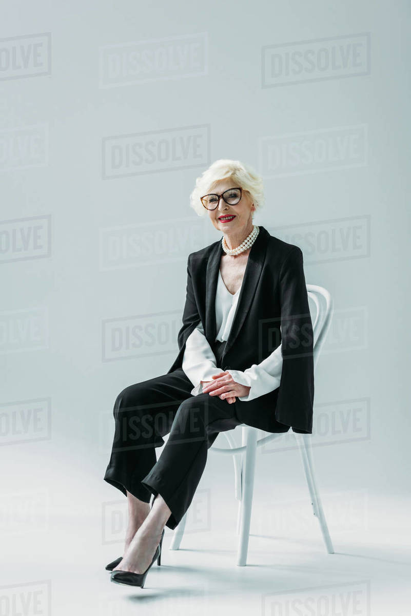 attractive elegant senior lady in black suit with pearl necklace, on ...