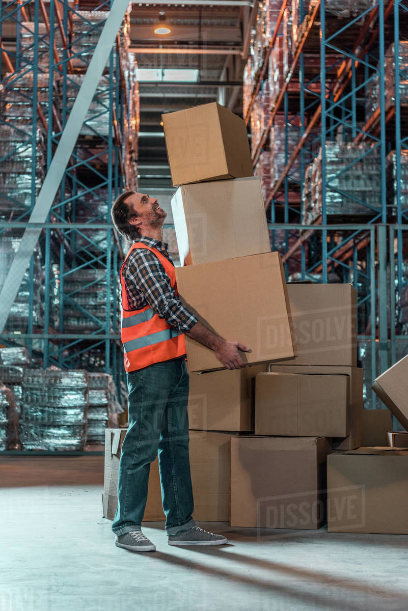 Side view of male warehouse worker holding stacked boxes - Royalty-free ...