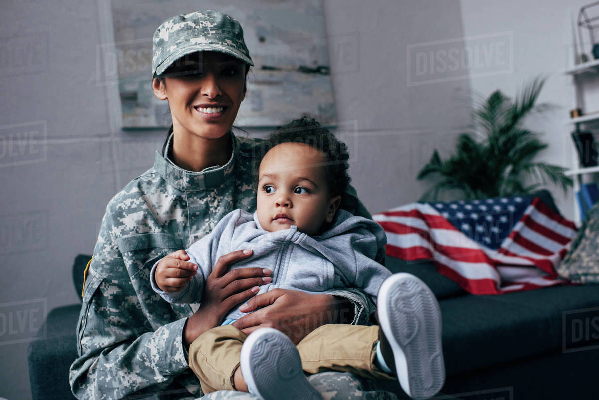 Smiling mother in military uniform with her little son at home, with ...