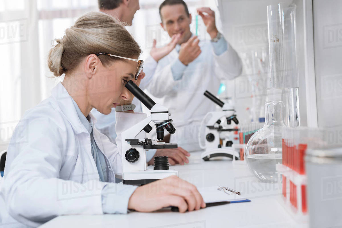 Professional scientist in lab coat working with microscope in chemical ...