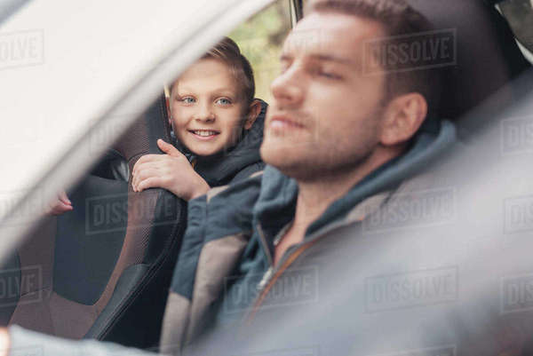 Selective focus of smiling boy looking at father driving car - Royalty ...