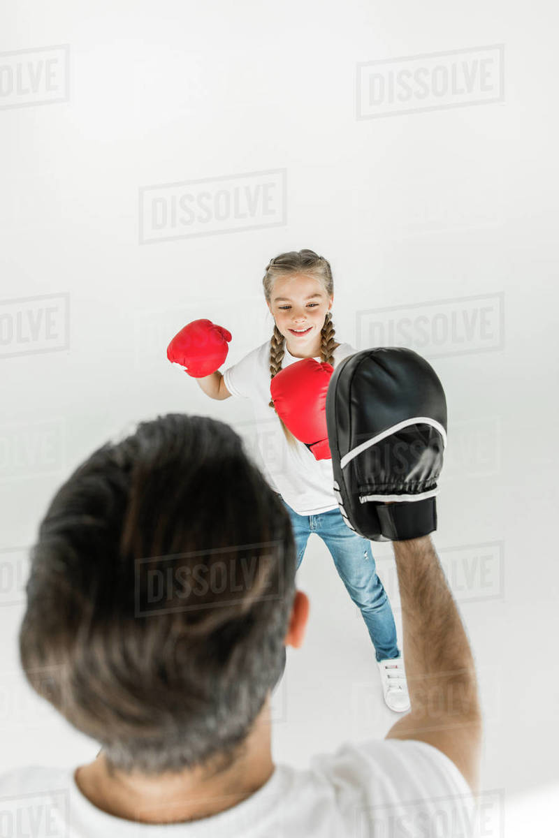Smiling little girl in boxing gloves training with father isolated on ...