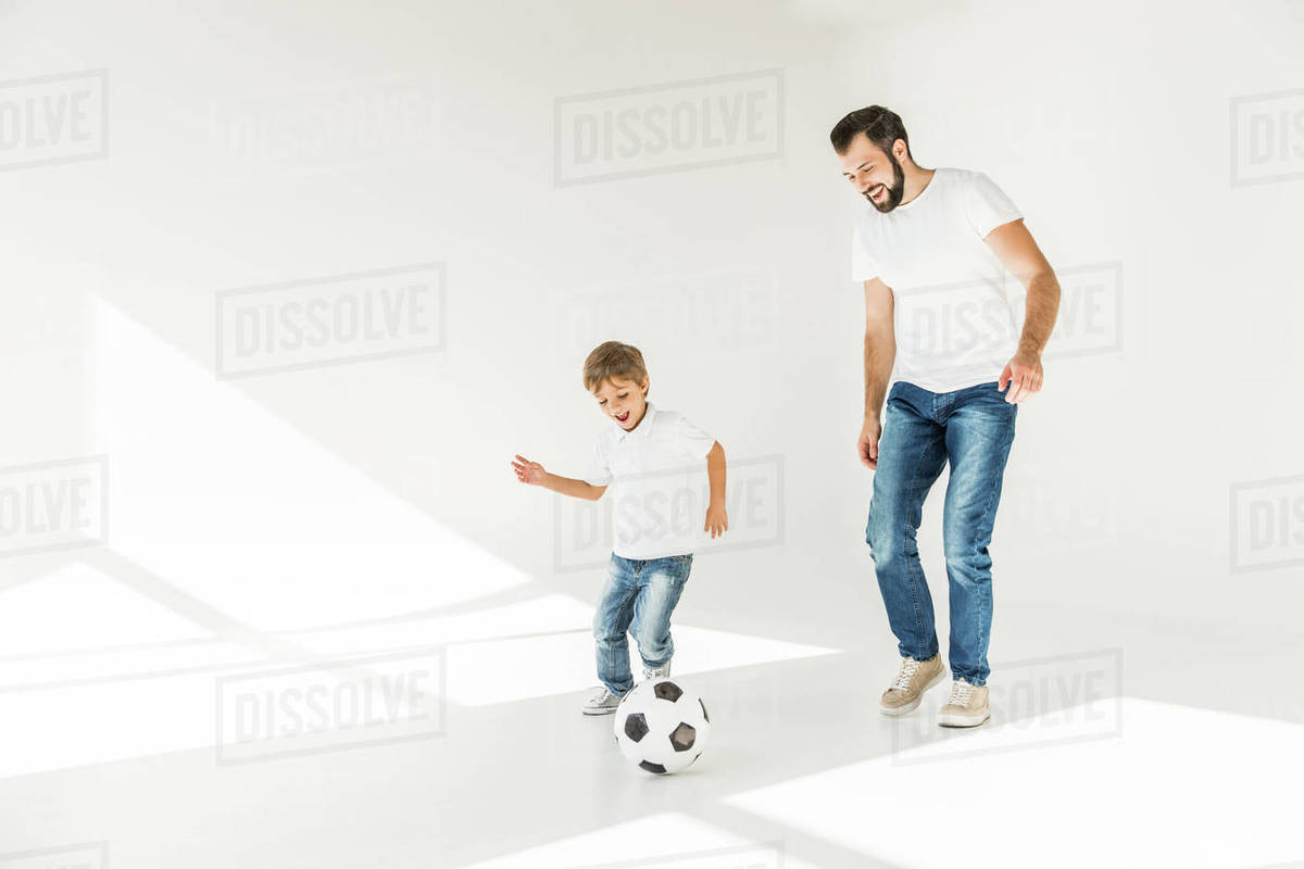 Happy father and son playing with soccer ball on white - Royalty-free ...