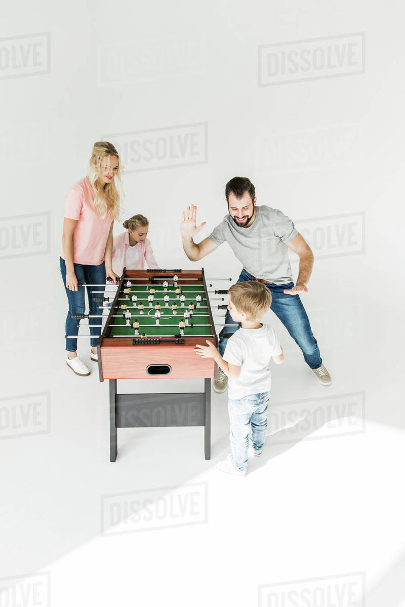 Happy family with two children playing foosball together isolated on ...