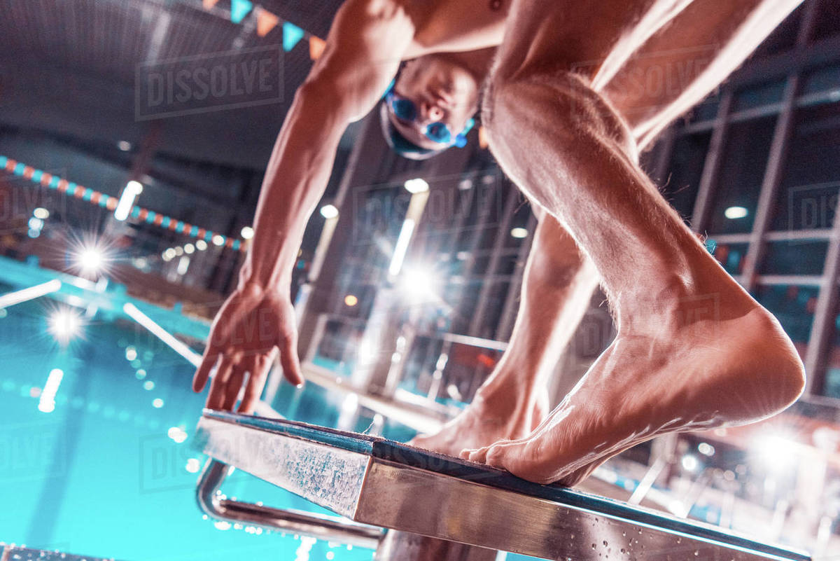 Bottom view of athletic male swimmer jumping into competition swimming ...
