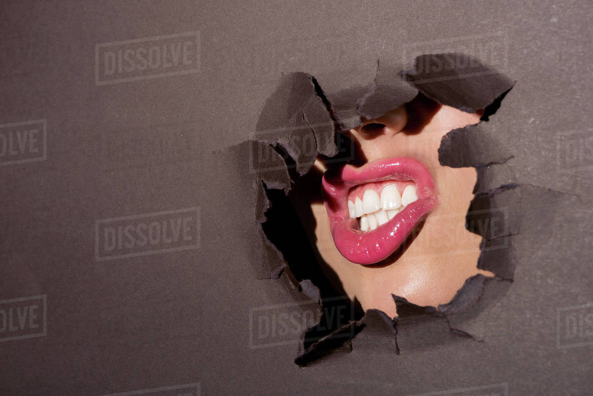 Pink lips of woman peeking out of ragged hole in dark paper - Royalty ...