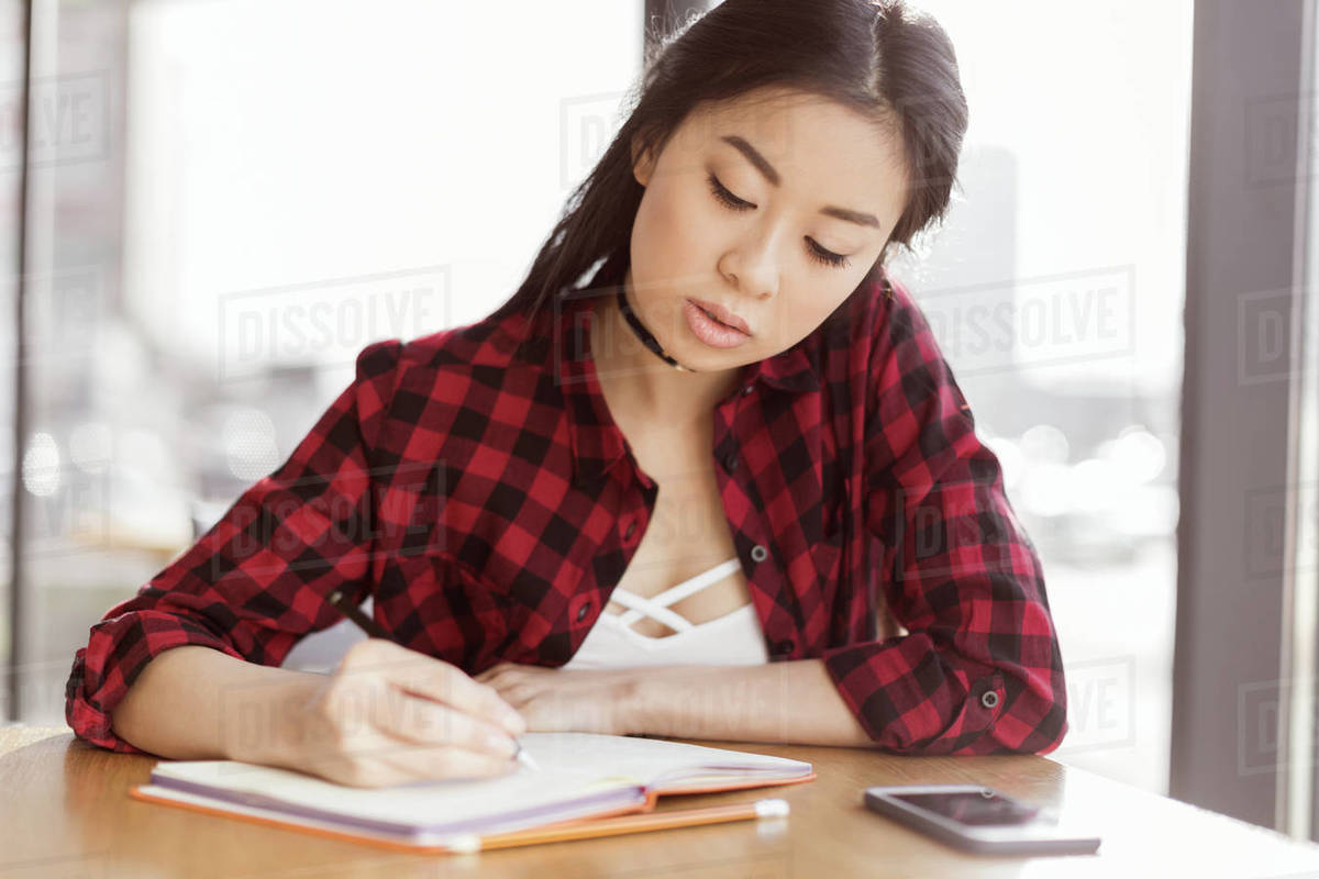 Attractive Asian student writing in diary and sitting in cafe - Royalty ...