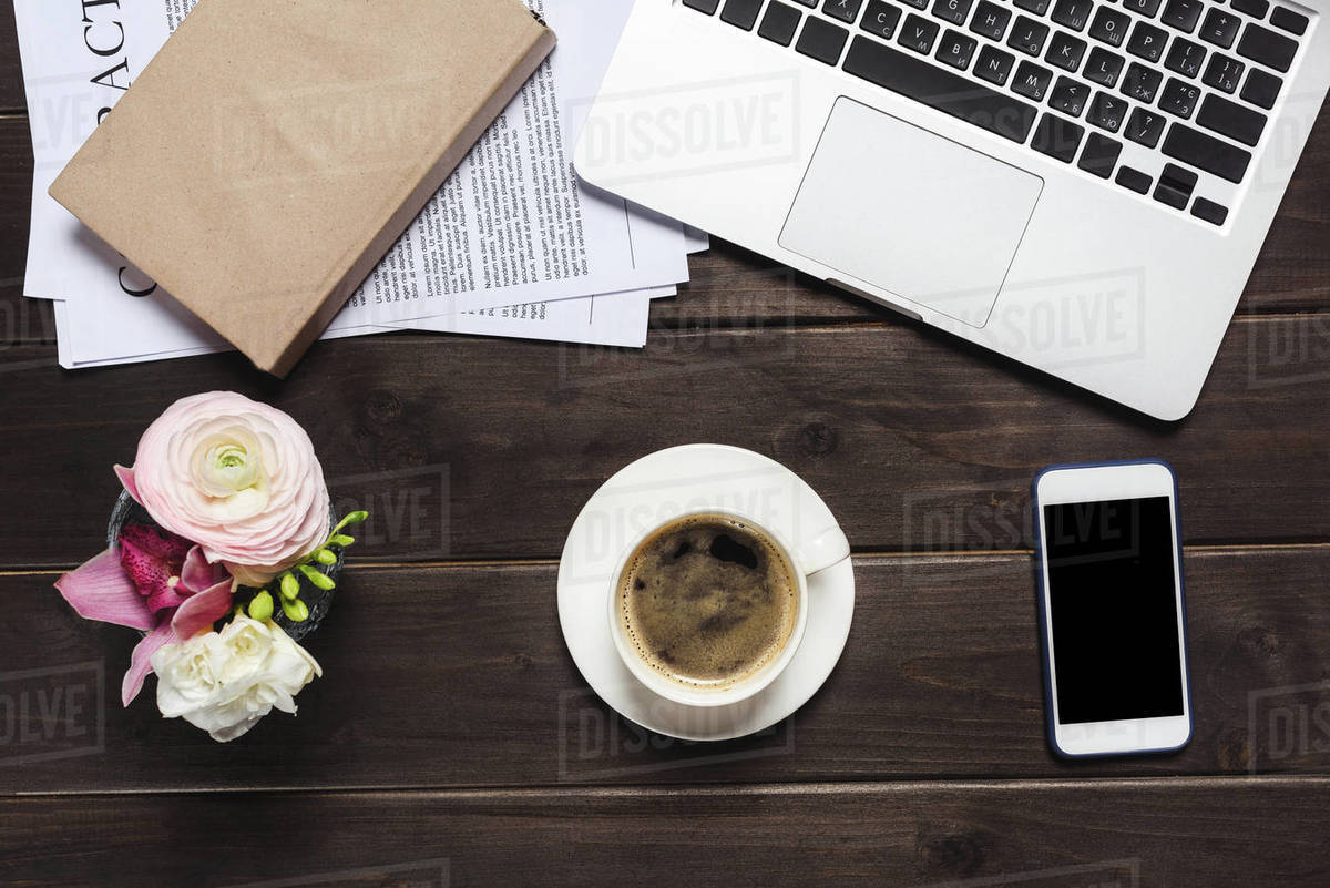 Top view of laptop, cup on coffee and smartphone on wooden table ...