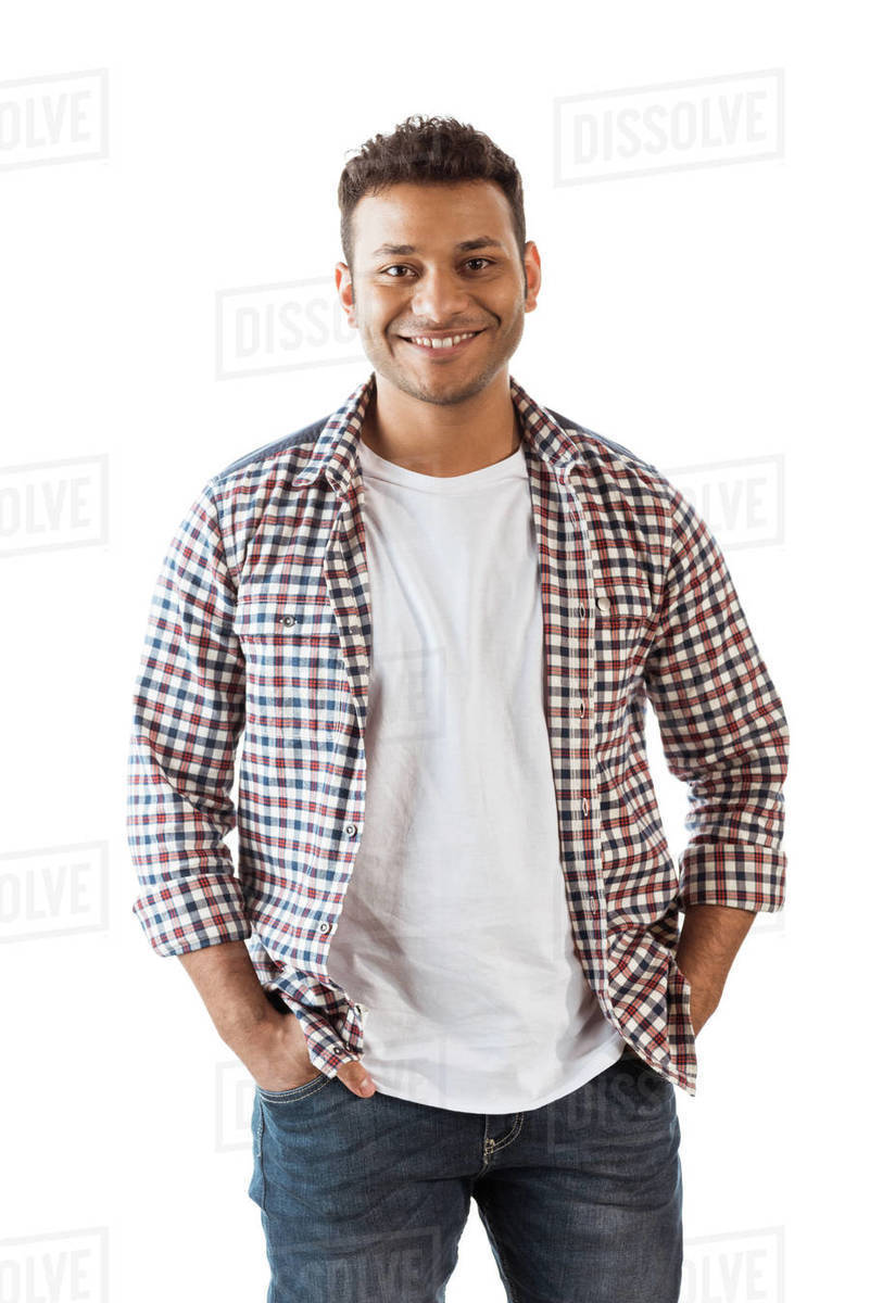 Portrait of handsome young man with hands in pockets smiling at camera ...