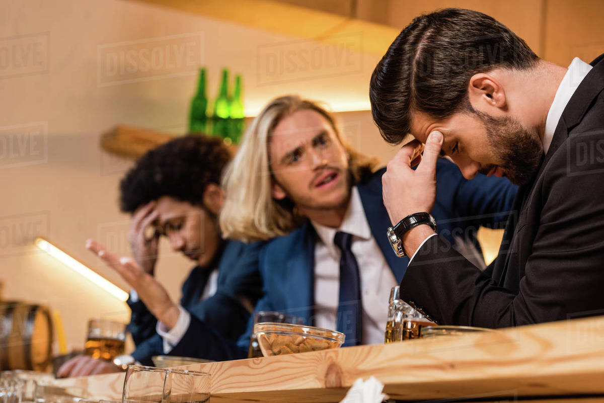 Upset businessmen talking while drinking beer in bar - Royalty-free ...