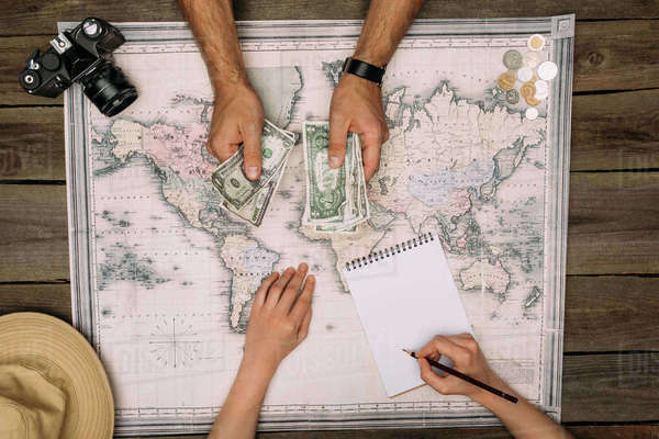 Couple of tourists planning a travel and counting money on a map ...