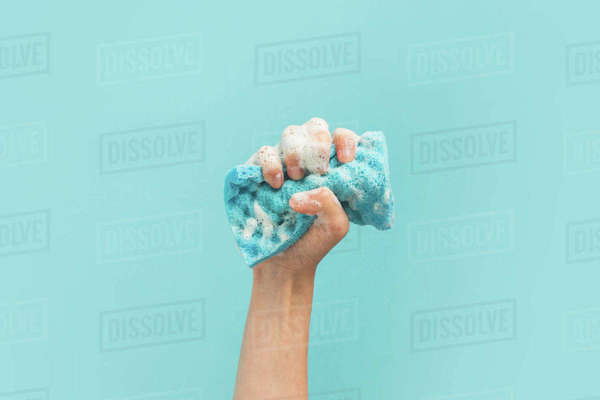 Cropped view of hand holding washing sponge with foam, isolated on blue ...