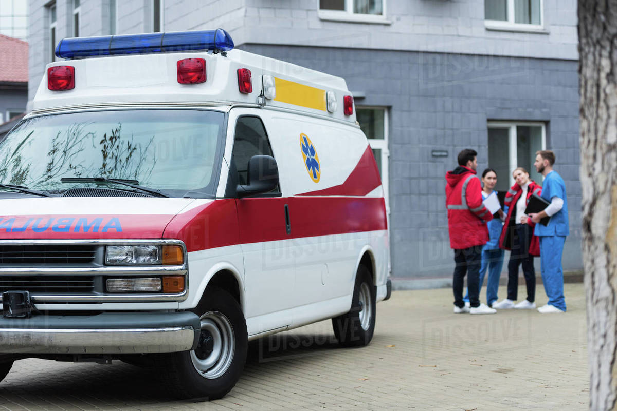 Four ambulance doctors talking and standing near car - Royalty-free ...