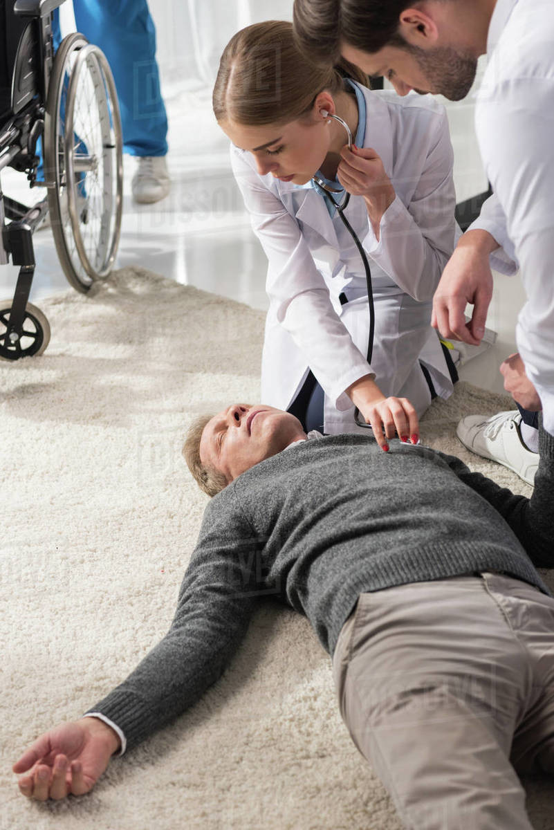 female doctor checking unconscious middle aged man palpitation with ...